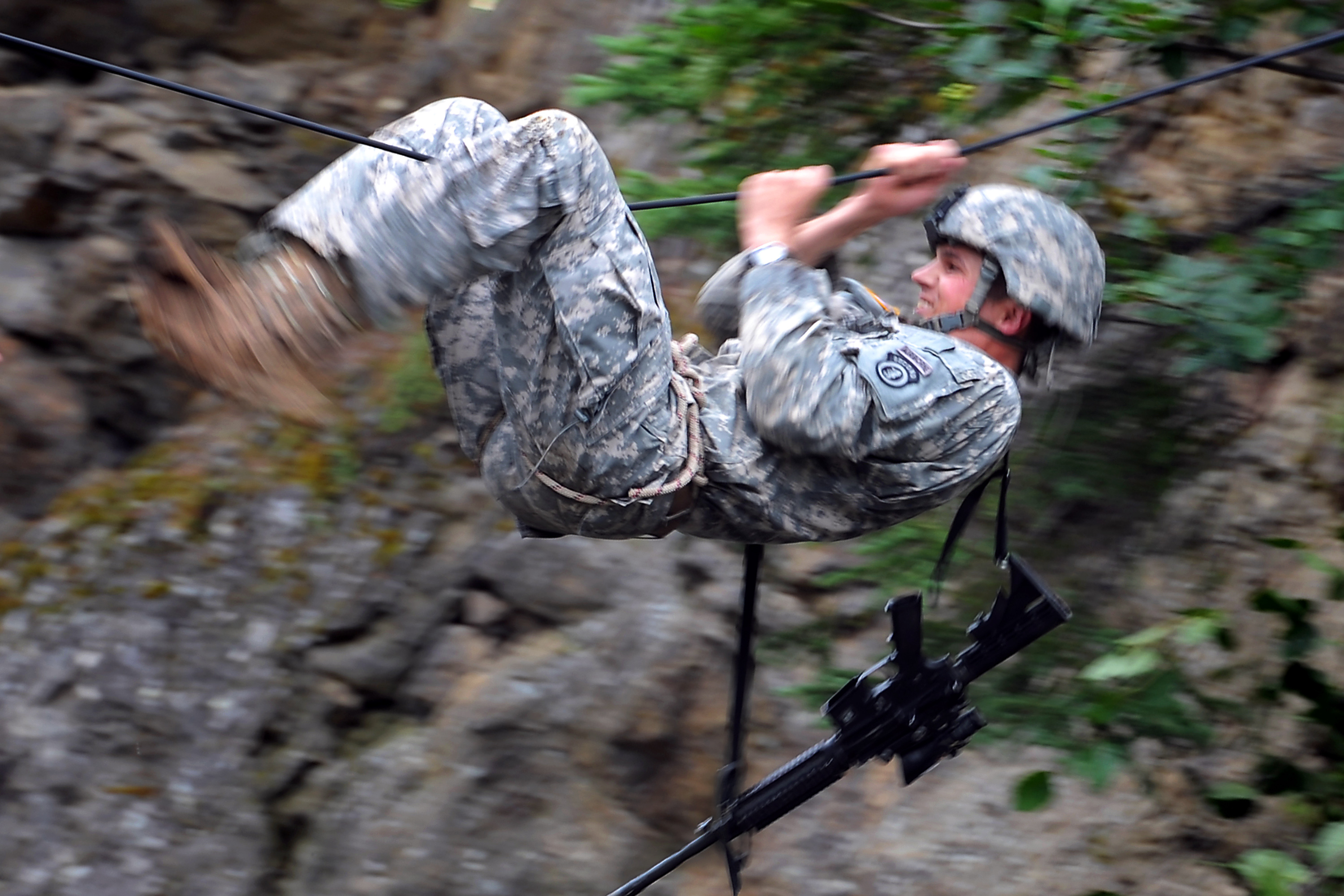 A soldier crosses a river on a single-rope bridge during his unit's ...
