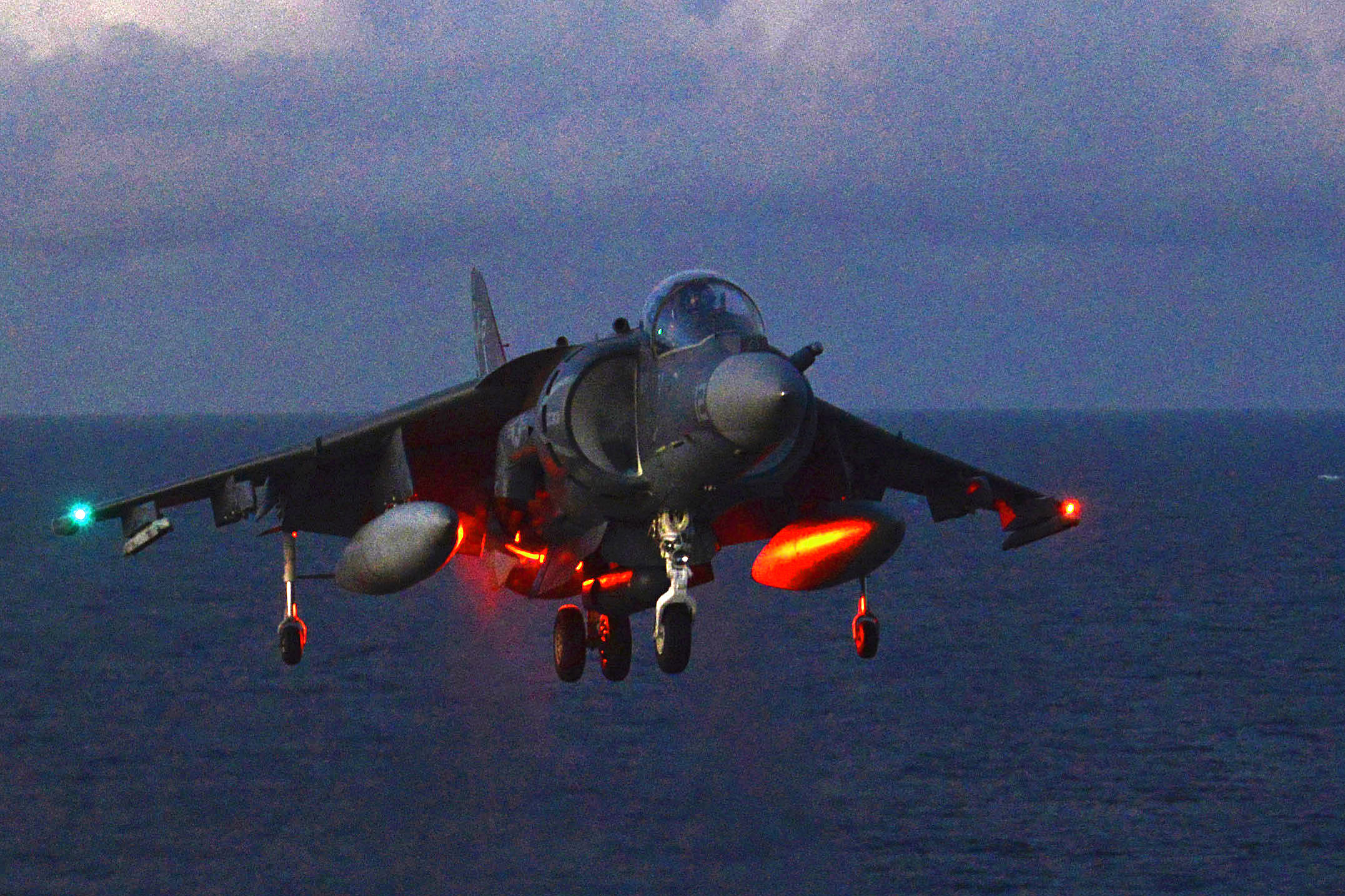 An AV-8B Harrier II lands on the flight deck during night operations ...