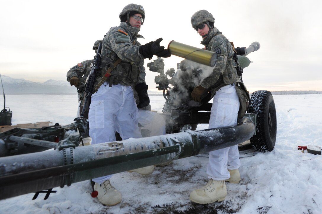 Army Pfc. Robert Moser, right, watches Army Spc. Alexander Santos throw ...