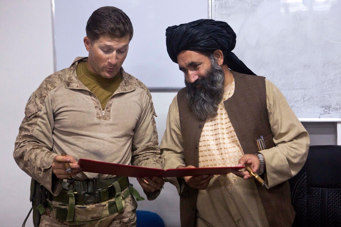 U.S. Marine Corps Capt. Charles Ferriera, left, presents a certificate ...