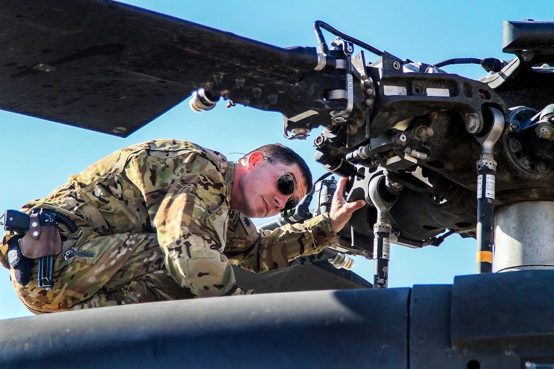 U.S. Army Capt. Andrew Wagner inspects the blades on a U.S. Army UH-60 ...