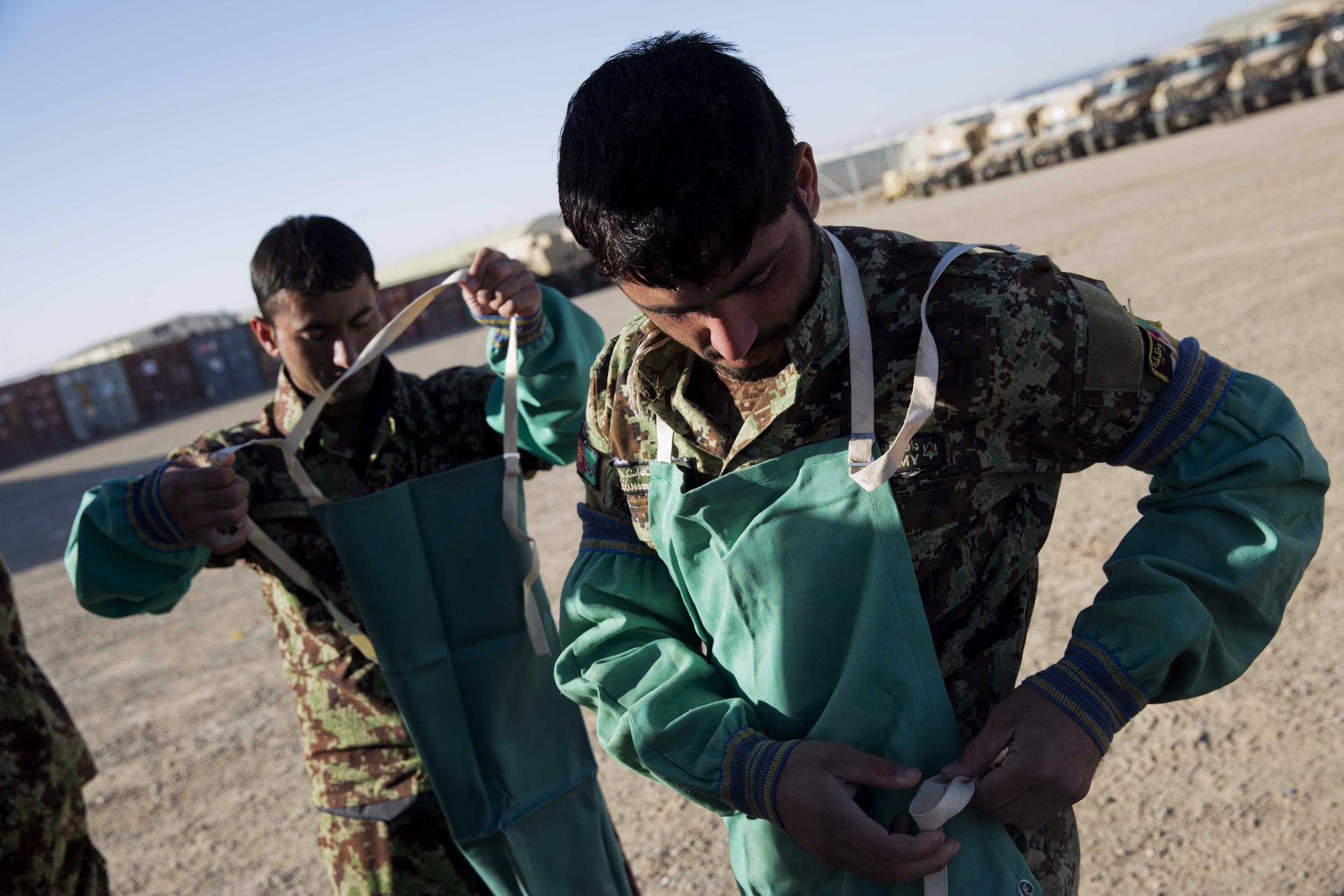 Afghan soldiers put on personal protective equipment during training on ...