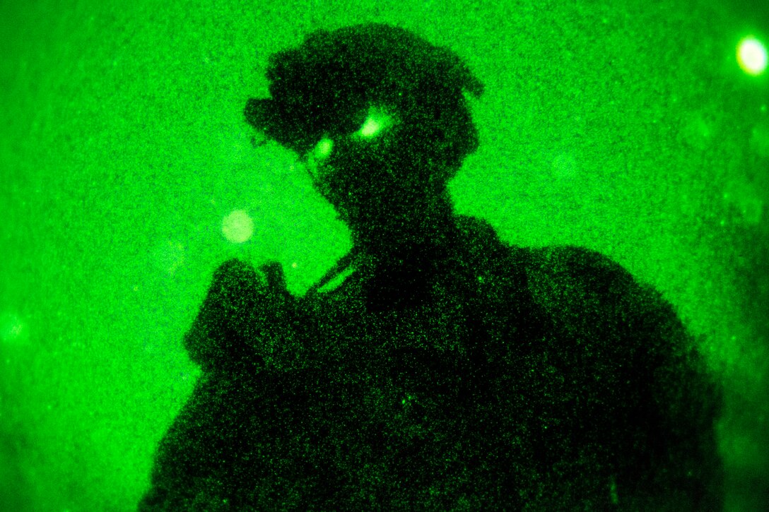 As seen through a night-vision device, a coalition force member helps ...