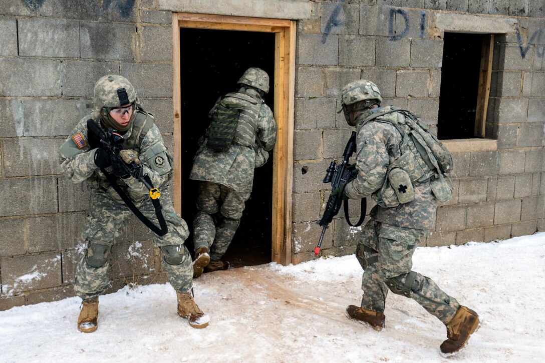 U.S. soldiers enter through a door while practicing building clearing ...