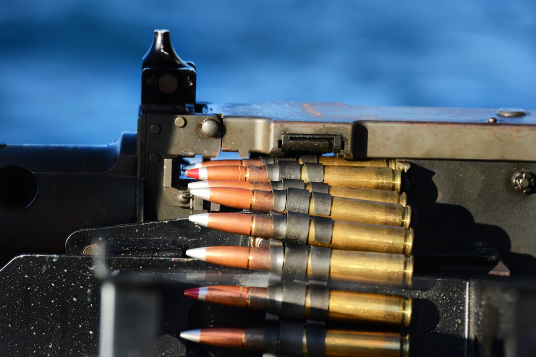U.S. sailors load ammunition into a .50-caliber machine gun during a ...