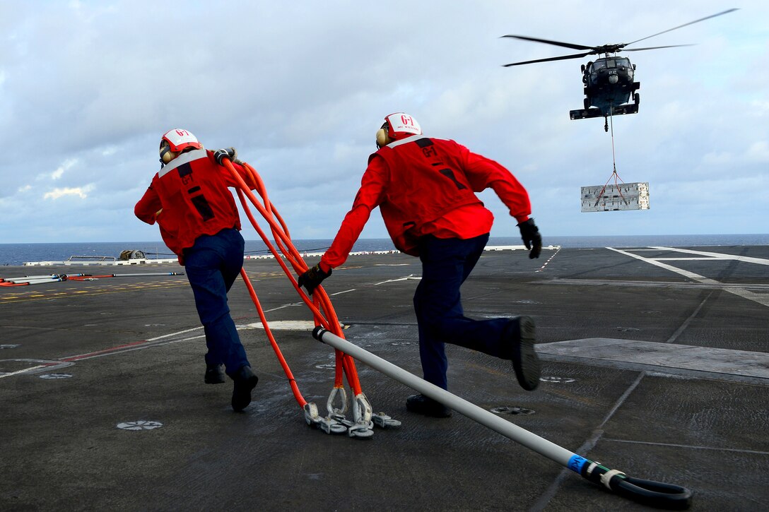 U.S. Navy sailors carry cargo pendants during an ammunition onload on ...