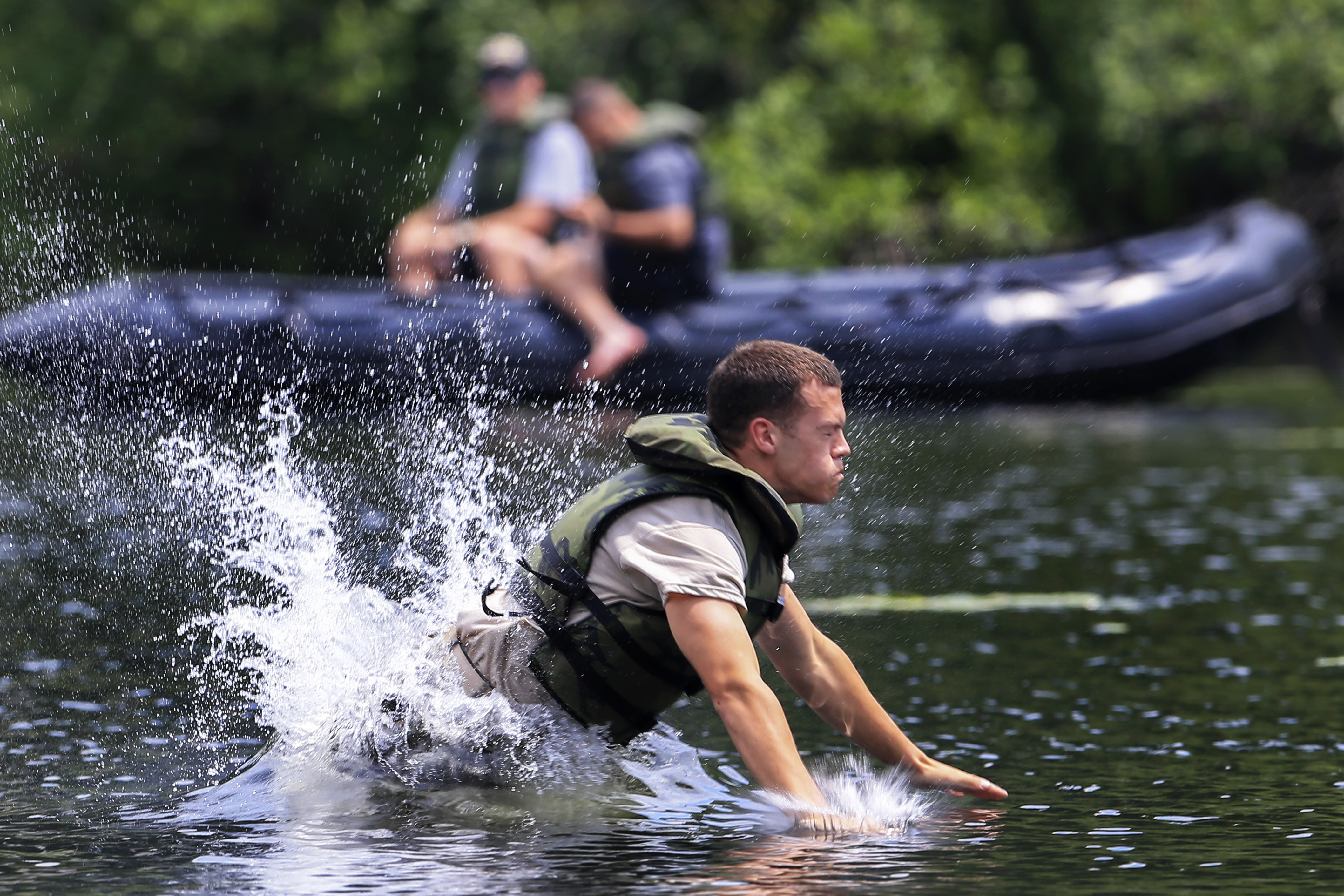 An Army cadet splashes into the water after releasing from a cable ...