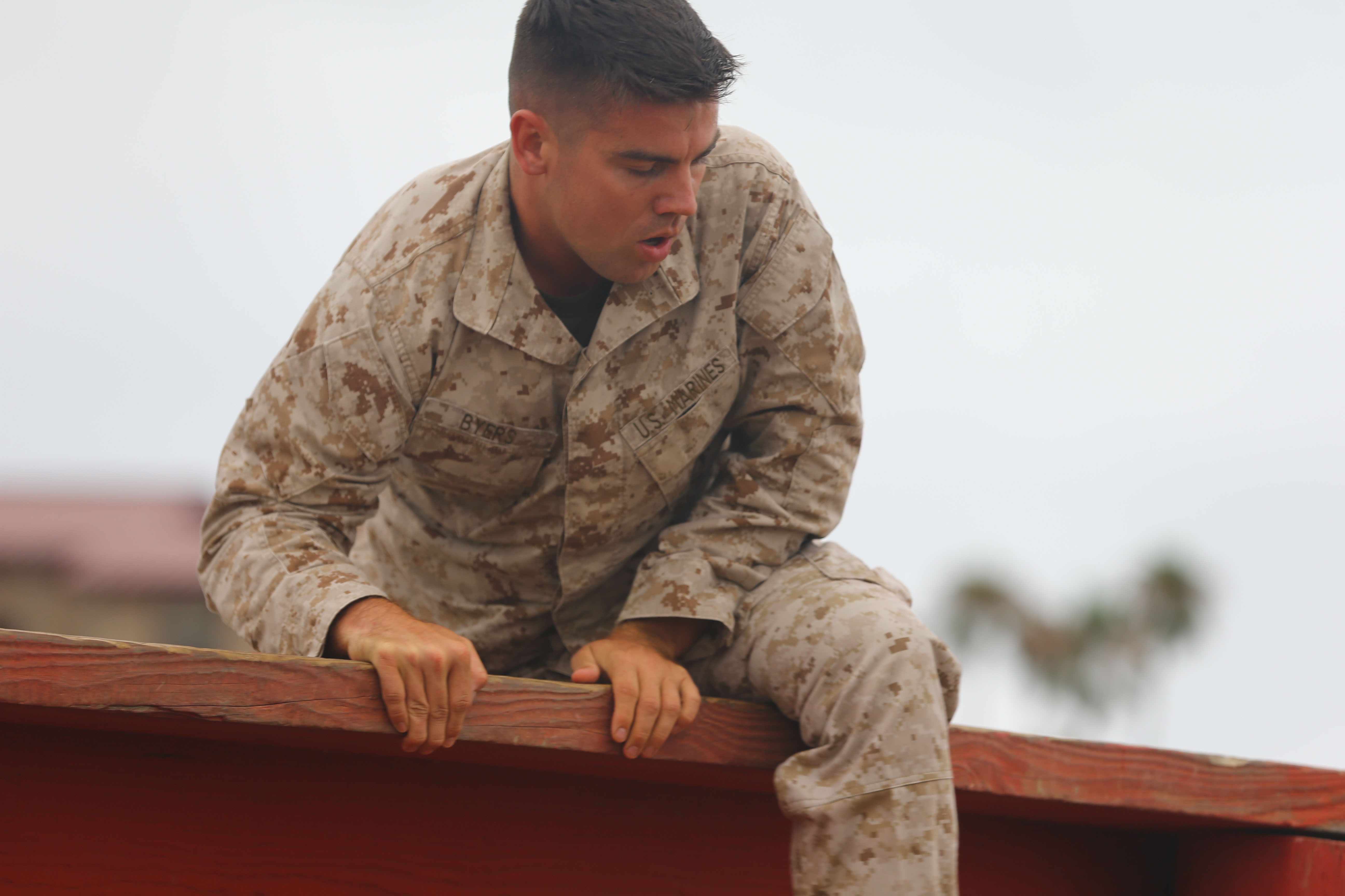 Sgt. Chad Byers, an intel analyst with the 11th MEU, climbs over a wall ...
