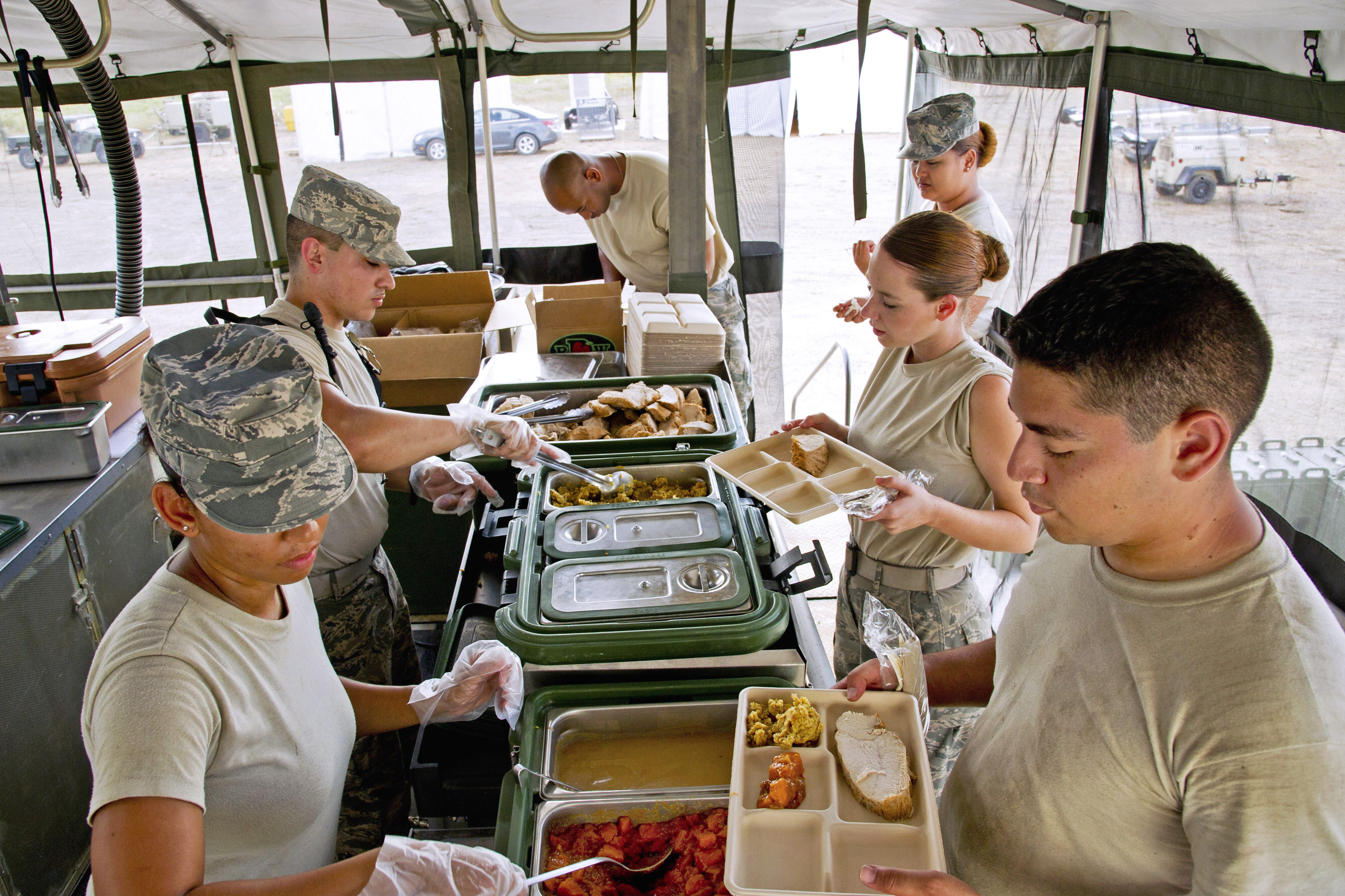 Airmen serve dinner in the field in a mobile kitchen trailer during ...