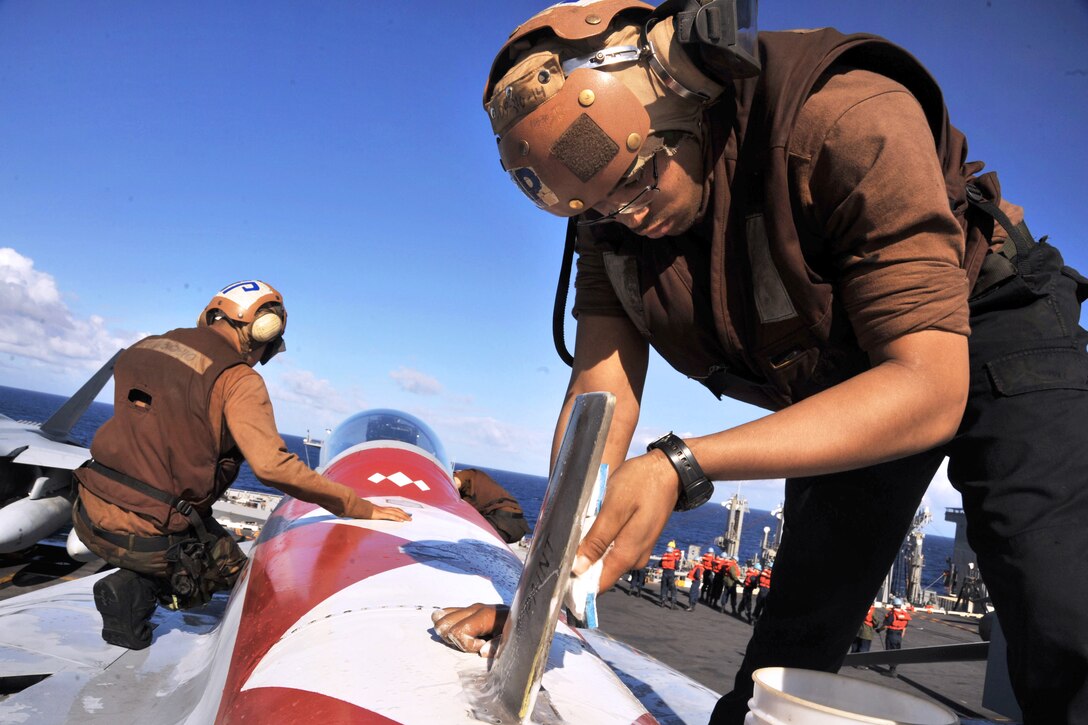 U.S. Navy Petty Officer 3rd Class Maurice Brown, right, washes the ...