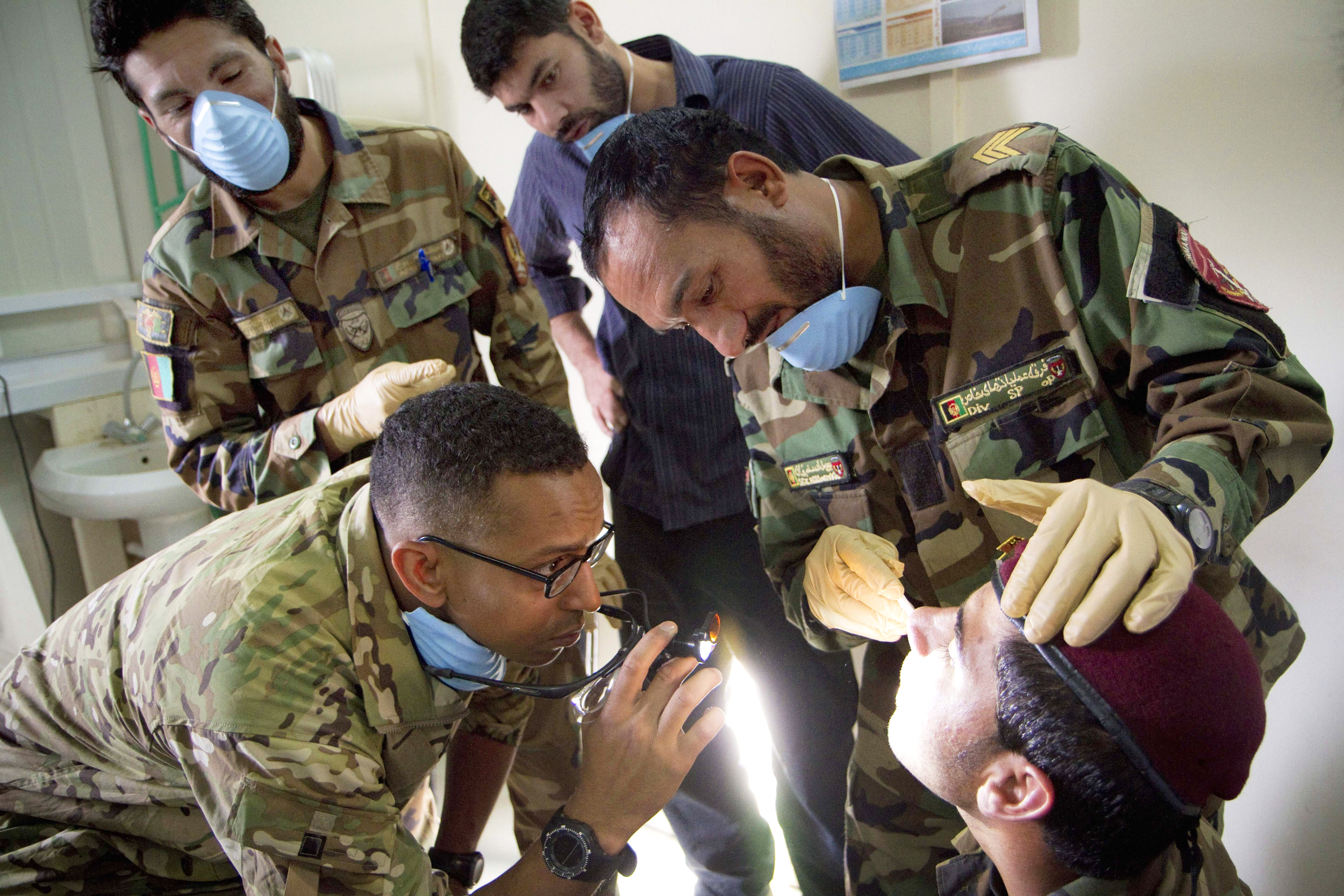 U.S. Army Capt. Abby Raymond, left, checks the work of an Afghan medic ...