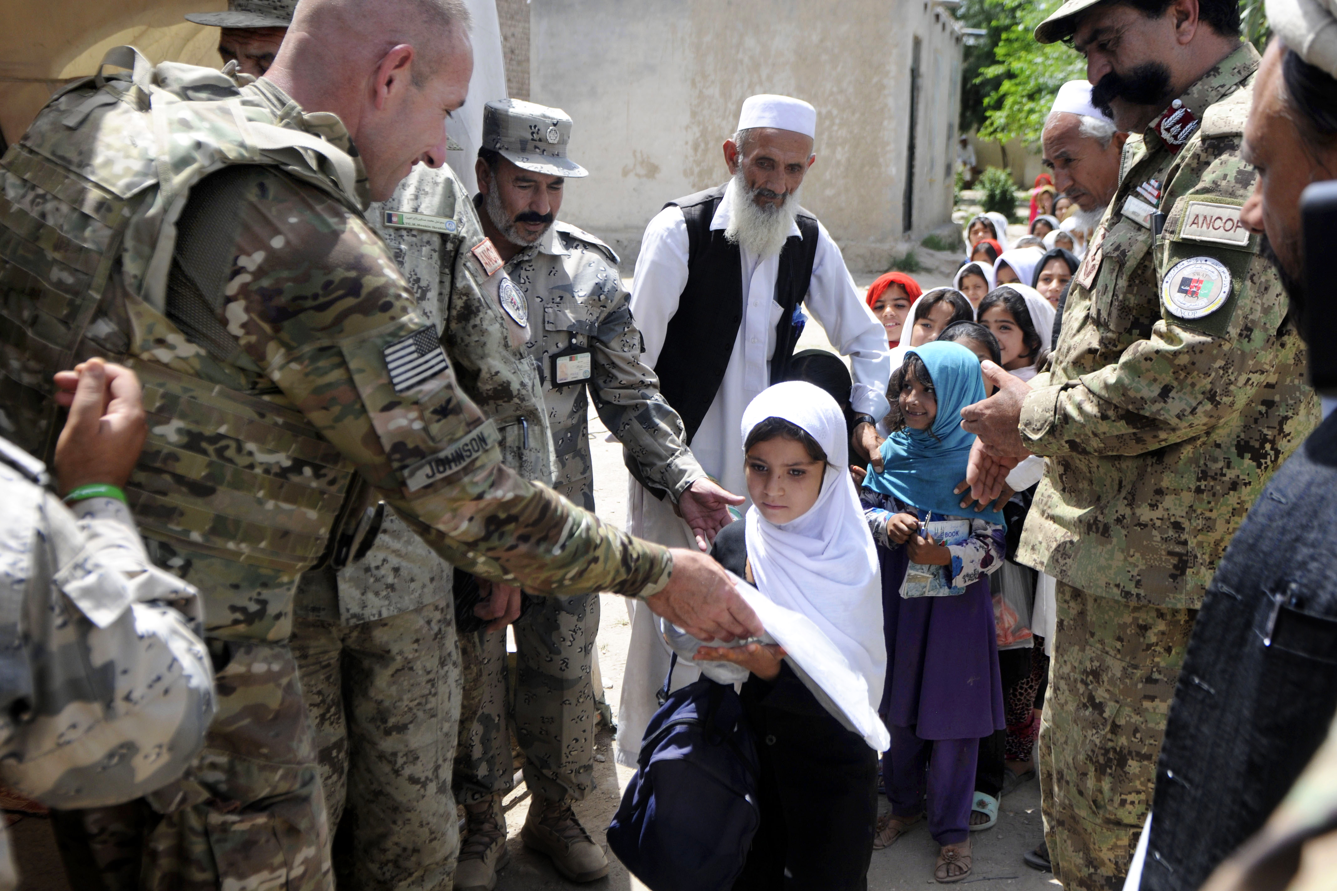 U.S. Army Col. Richard Johnson, left, and Afghan border police hand out ...
