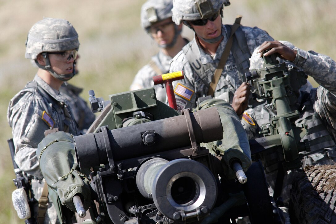 Soldiers work to set up their 105 mm howitzer following an airdrop onto ...