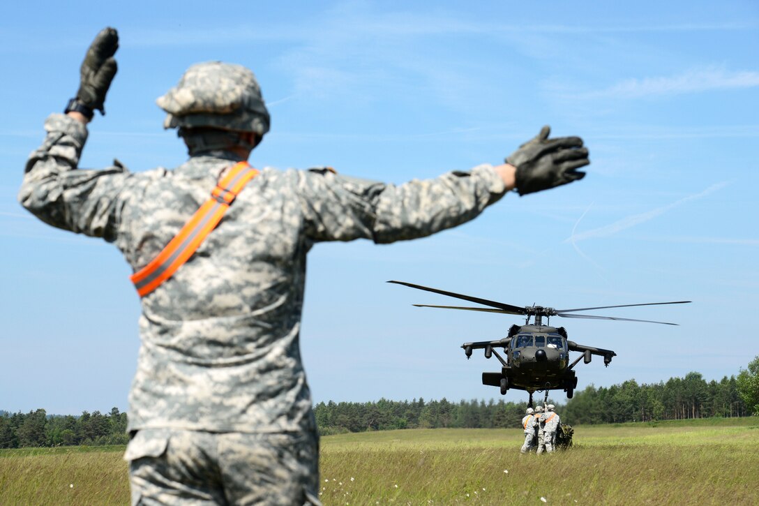 U.S. soldiers give hand signals to the pilots of a UH-60 Black Hawk ...