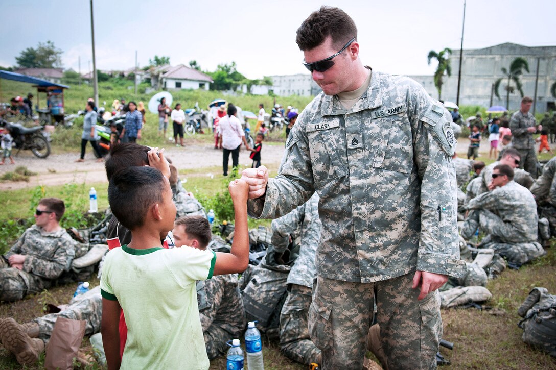 U.S. Army Staff Sgt. Forest Clark fist bumps with a local boy after ...