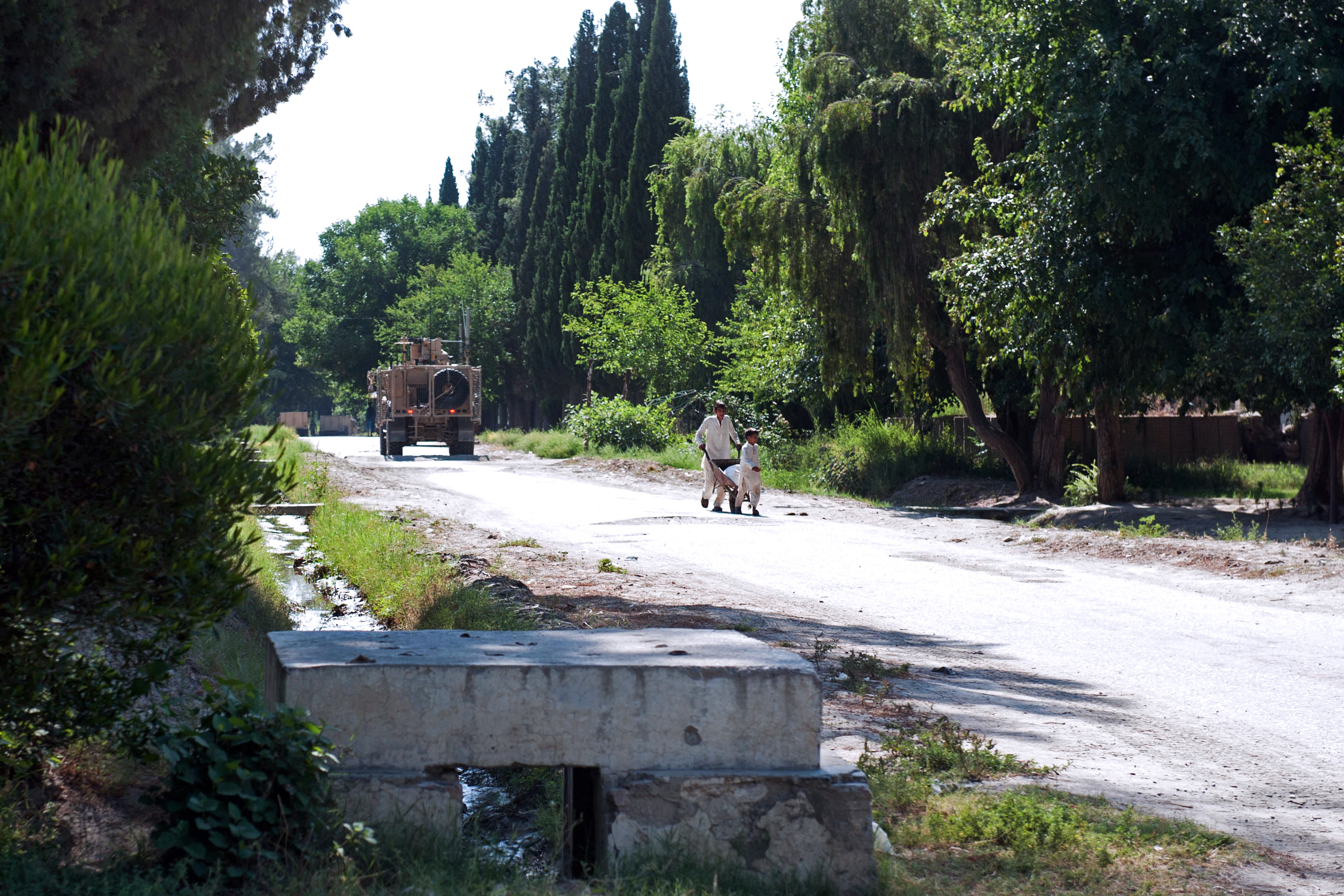 An Afghan farmer and boy watch as U.S. and Afghan army soldiers patrol ...