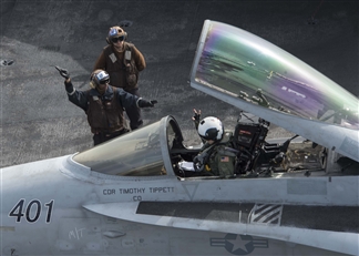 U.S. Navy plane captain uses hand signals to communicate with the pilot ...