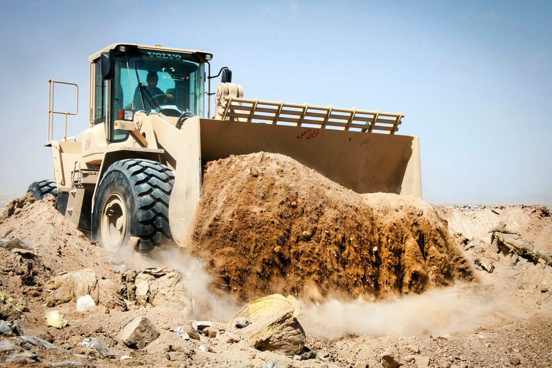 An Afghan national army heavy equipment operator levels the ground ...