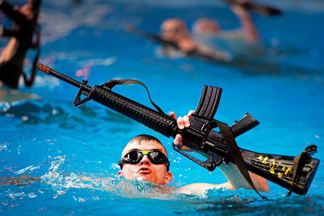 Marine Corps Cpl. Tanner Seitz performs a rifle swim as part of aquatic ...