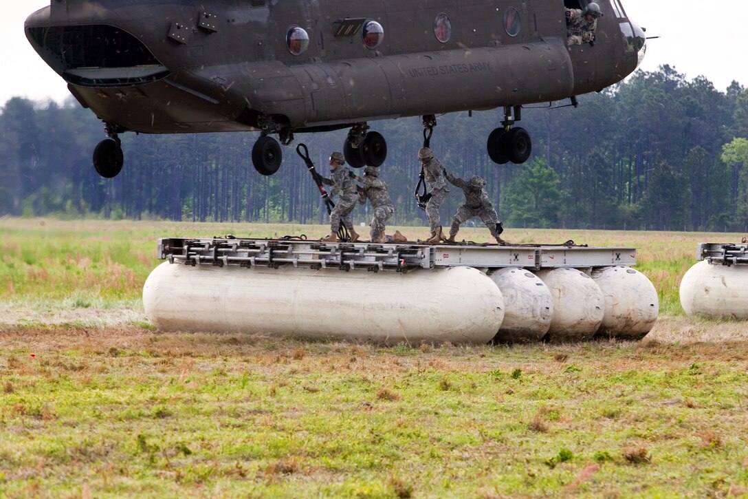 Soldiers attach a portion of a modular causeway system to a CH-47 ...