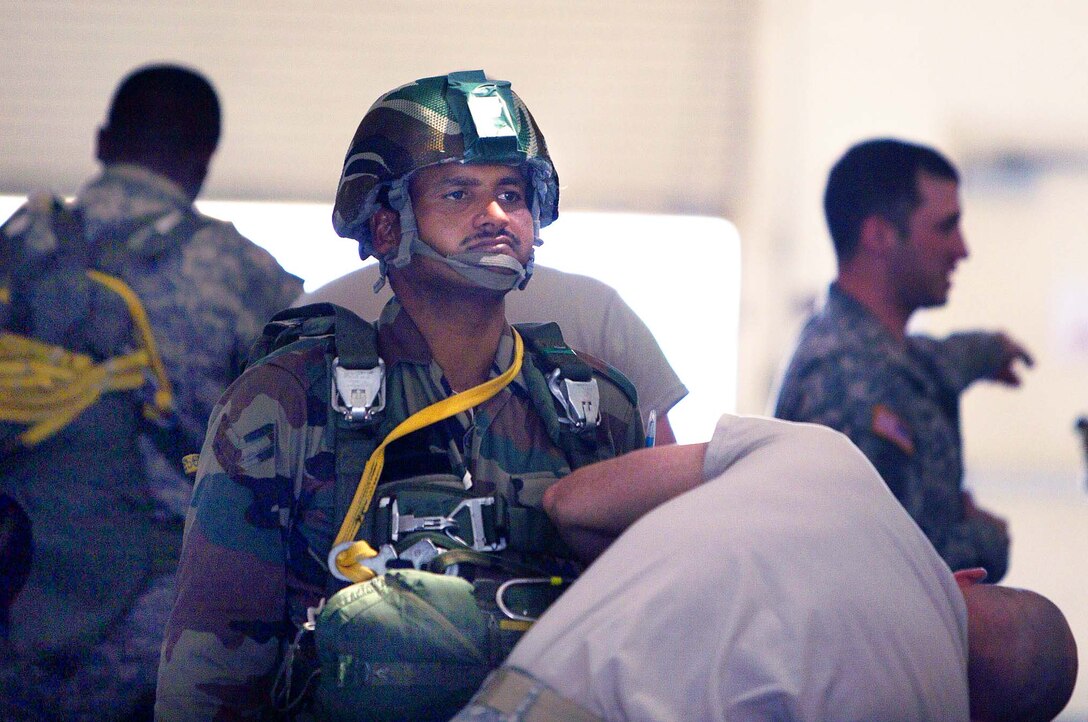 An Indian army paratrooper gets his parachute inspected by a U.S. Army jumpmaster before an ...