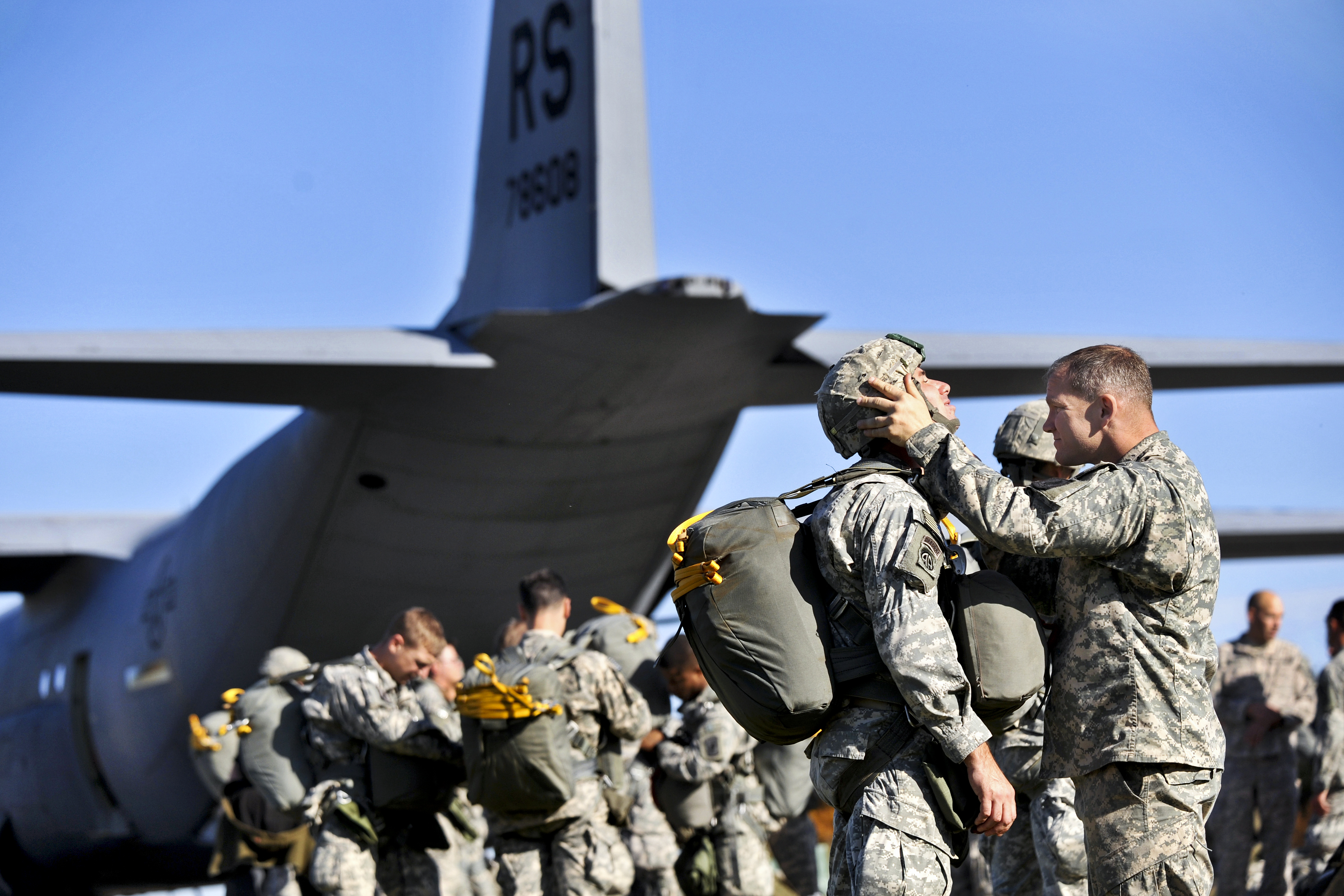 U.S. soldiers help each other inspect their equipment before a combat ...