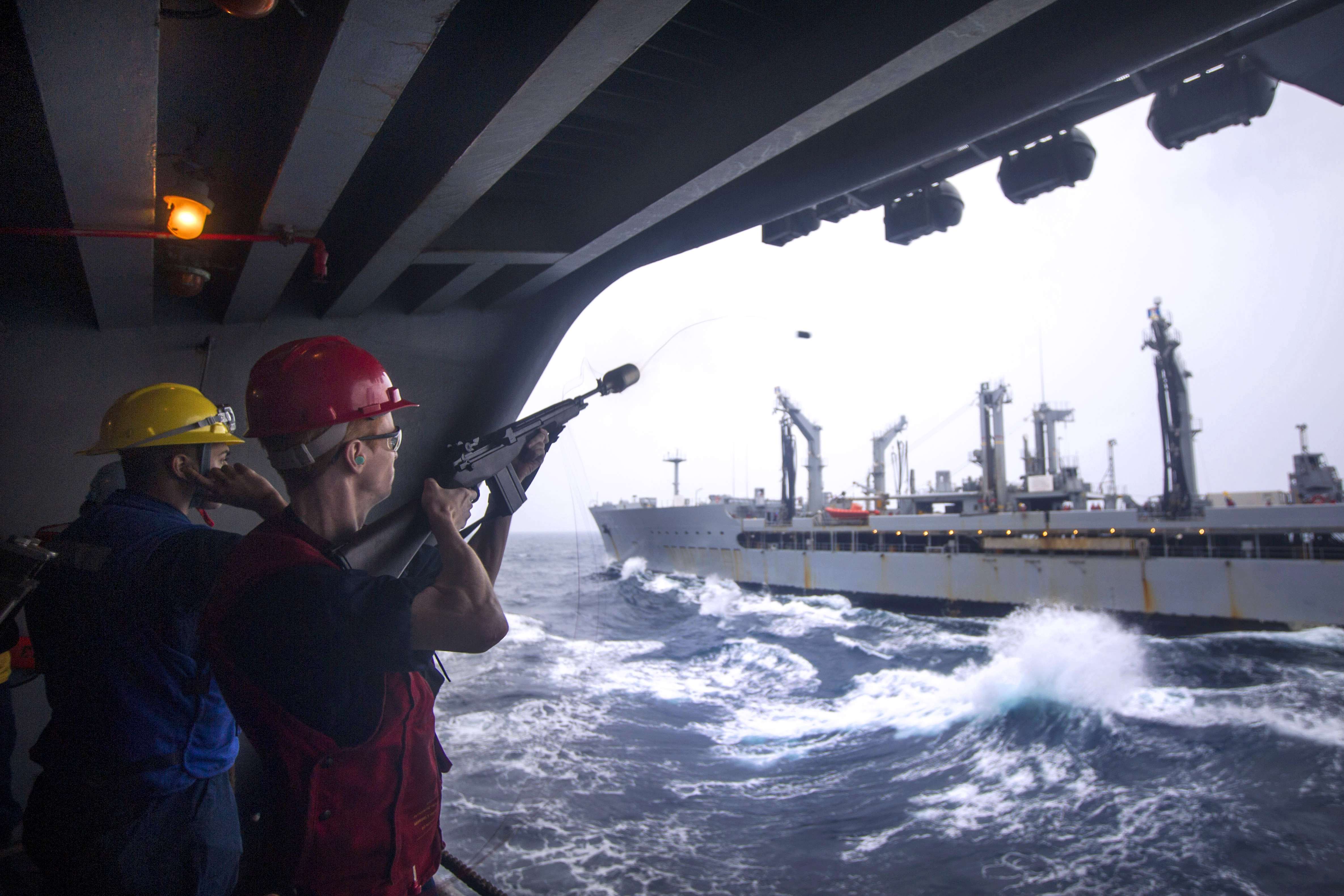U.S. Navy Petty Officer 2nd Class Rusty Ruf uses an M-14 rifle to fire ...