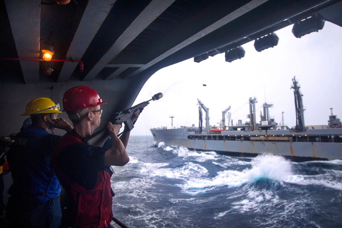 U.S. Navy Petty Officer 2nd Class Rusty Ruf uses an M-14 rifle to fire ...