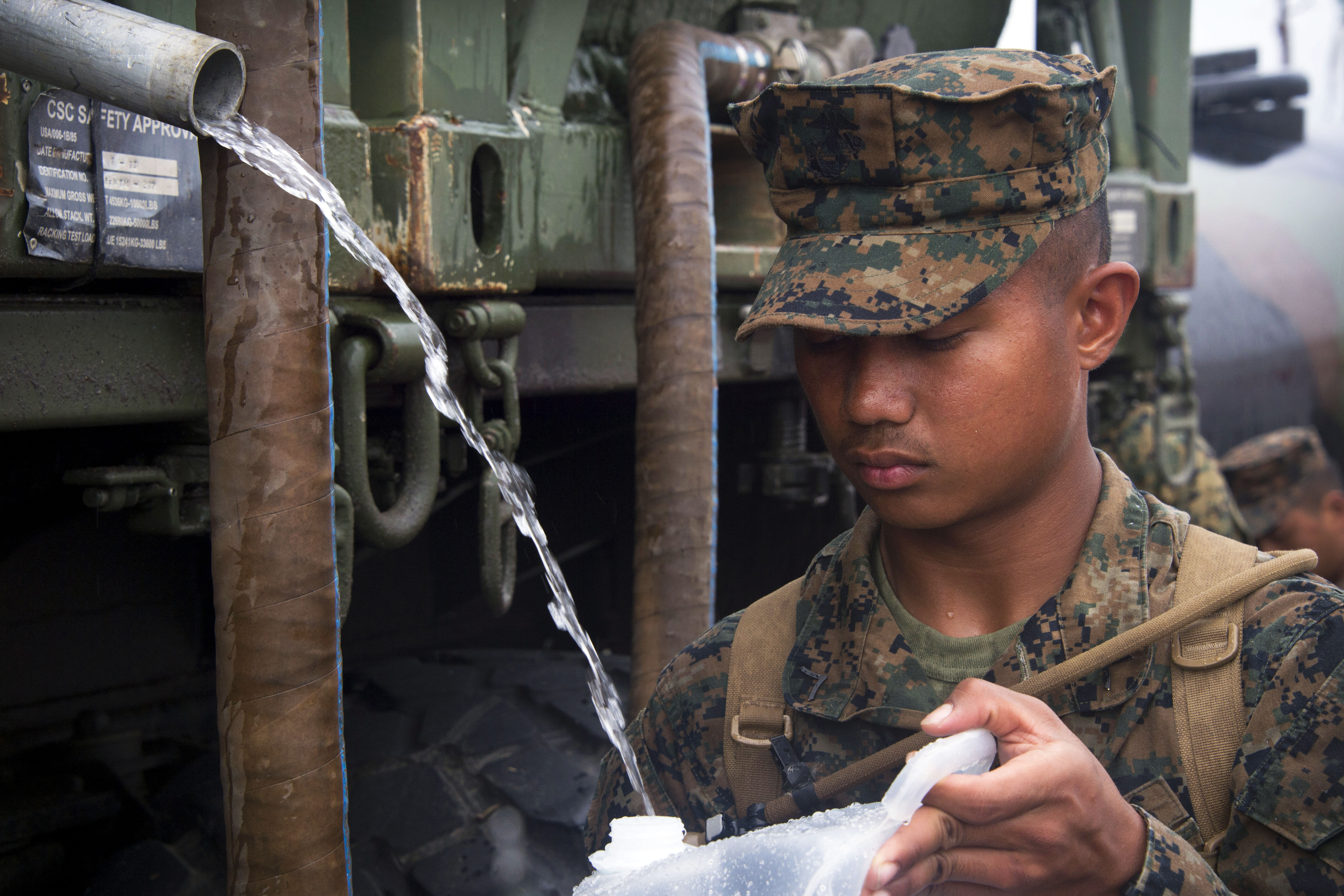 U.S. Marine Corps Pfc. John Evans fills and distributes fresh water to ...
