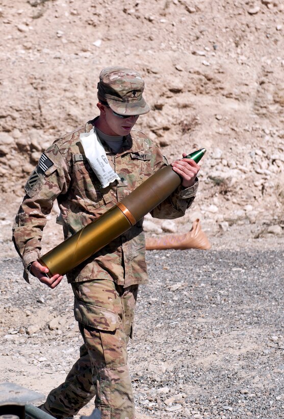 U.S. Army Spc. Bradley Grundel carries a 105-mm M119A2 howitzer round ...