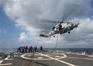U.S. Navy sailors tend a fuel hose for an inflight refueling of an MH ...