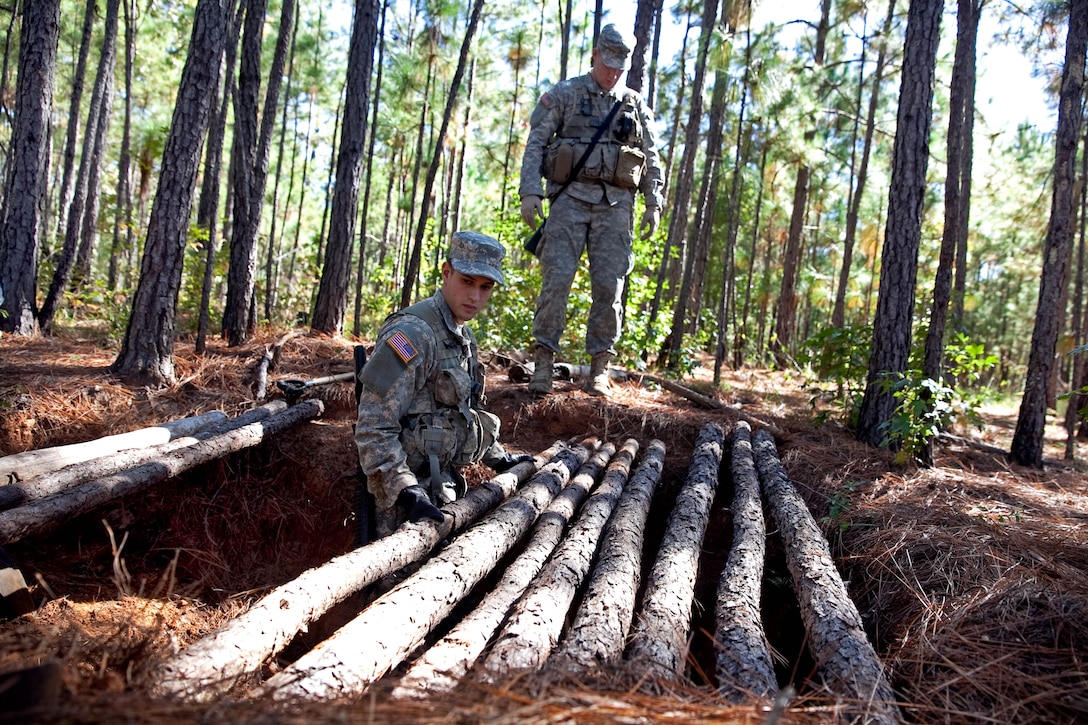 Army Sgt. Matthew Mararrio, foreground, moves logs over a subsurface ...