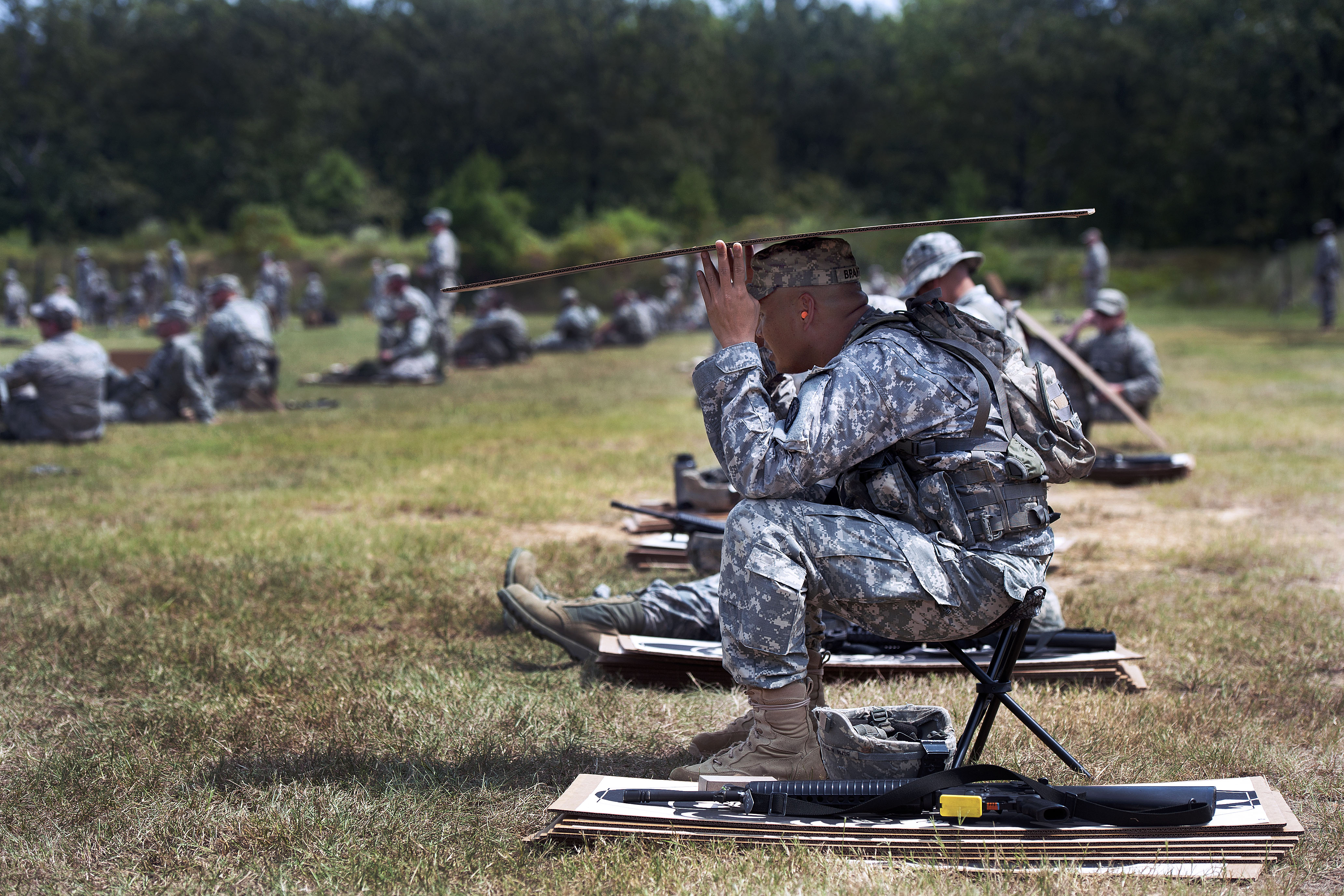 Army 1st Sgt. Ronald Brantley uses a target to provide shade while ...