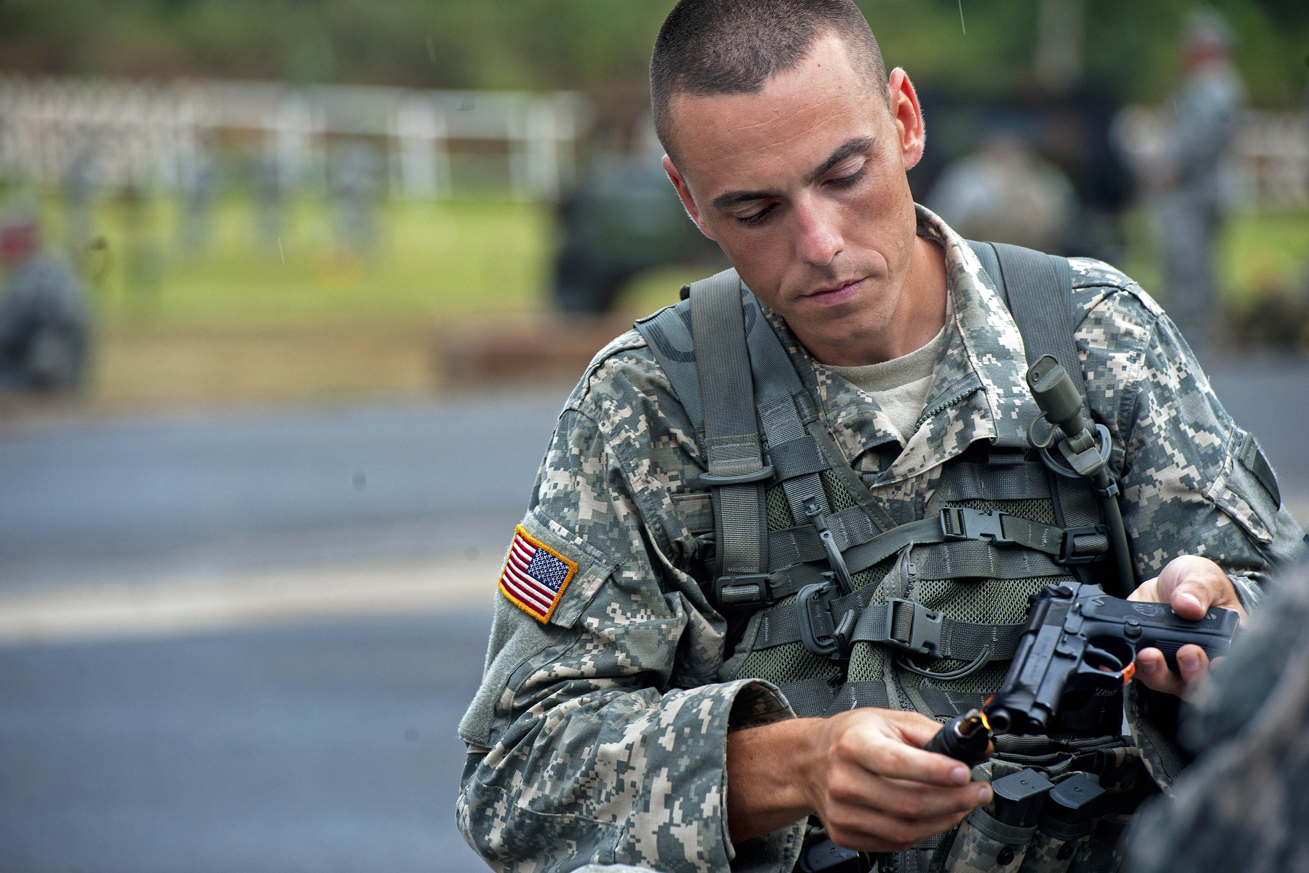 Army Spc. Joseph Miller uses a lighter to dull the finish on the sights ...