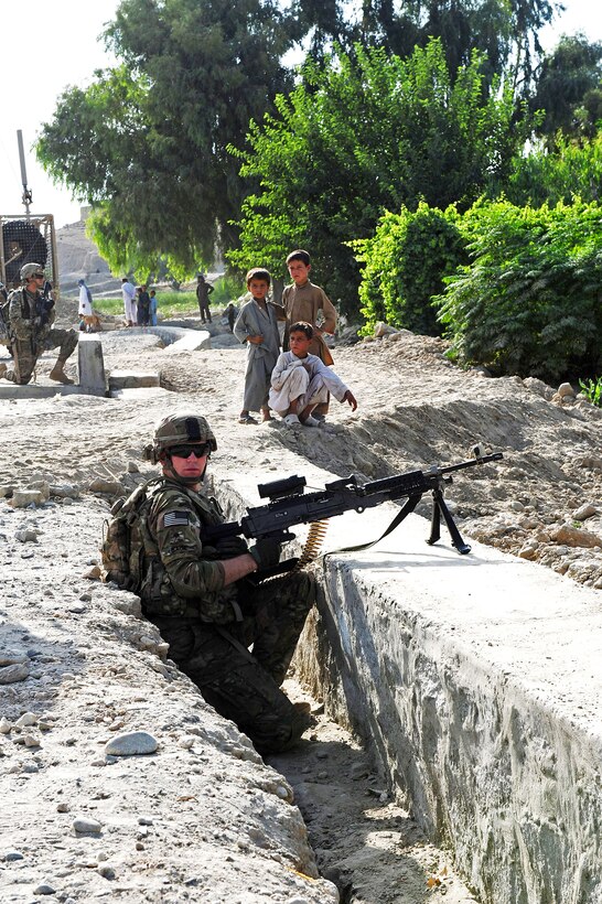 Afghan children watch as U.S. Army Spc. Casey Sage provides security ...