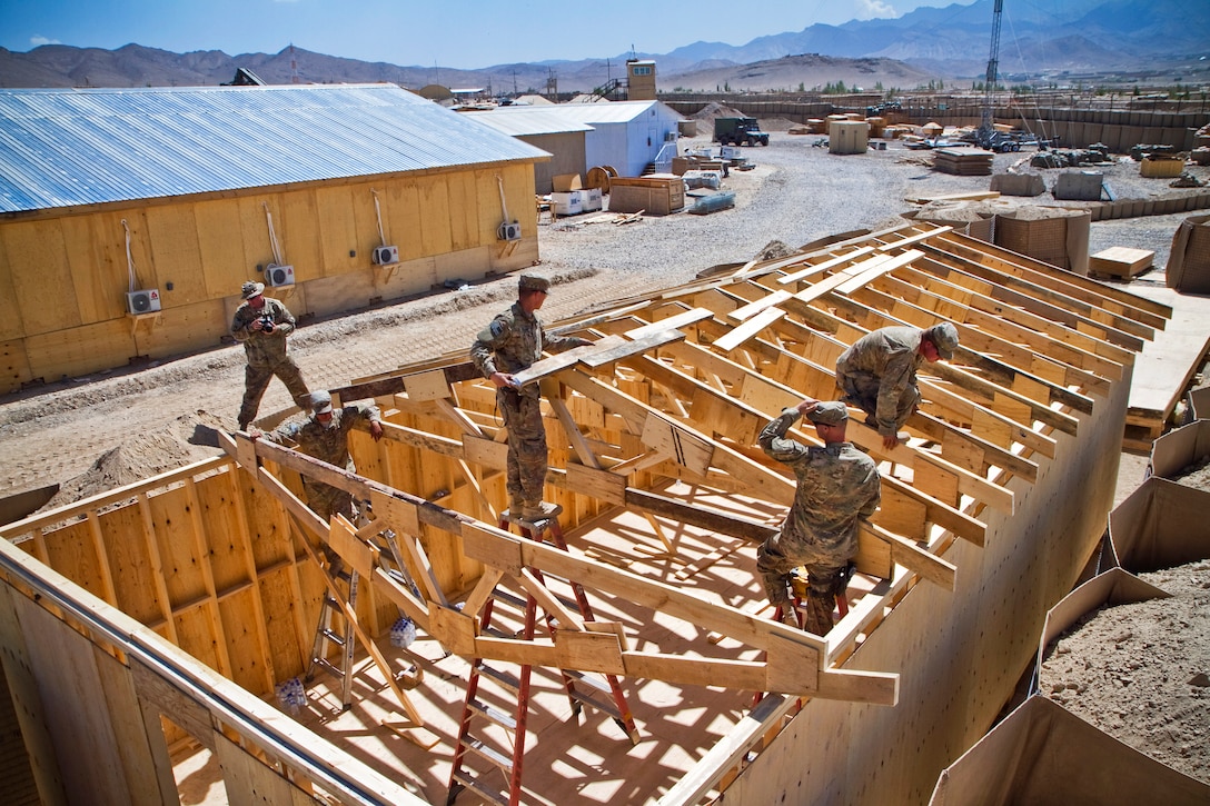 U.S. soldiers move trusses into place during the construction of living ...