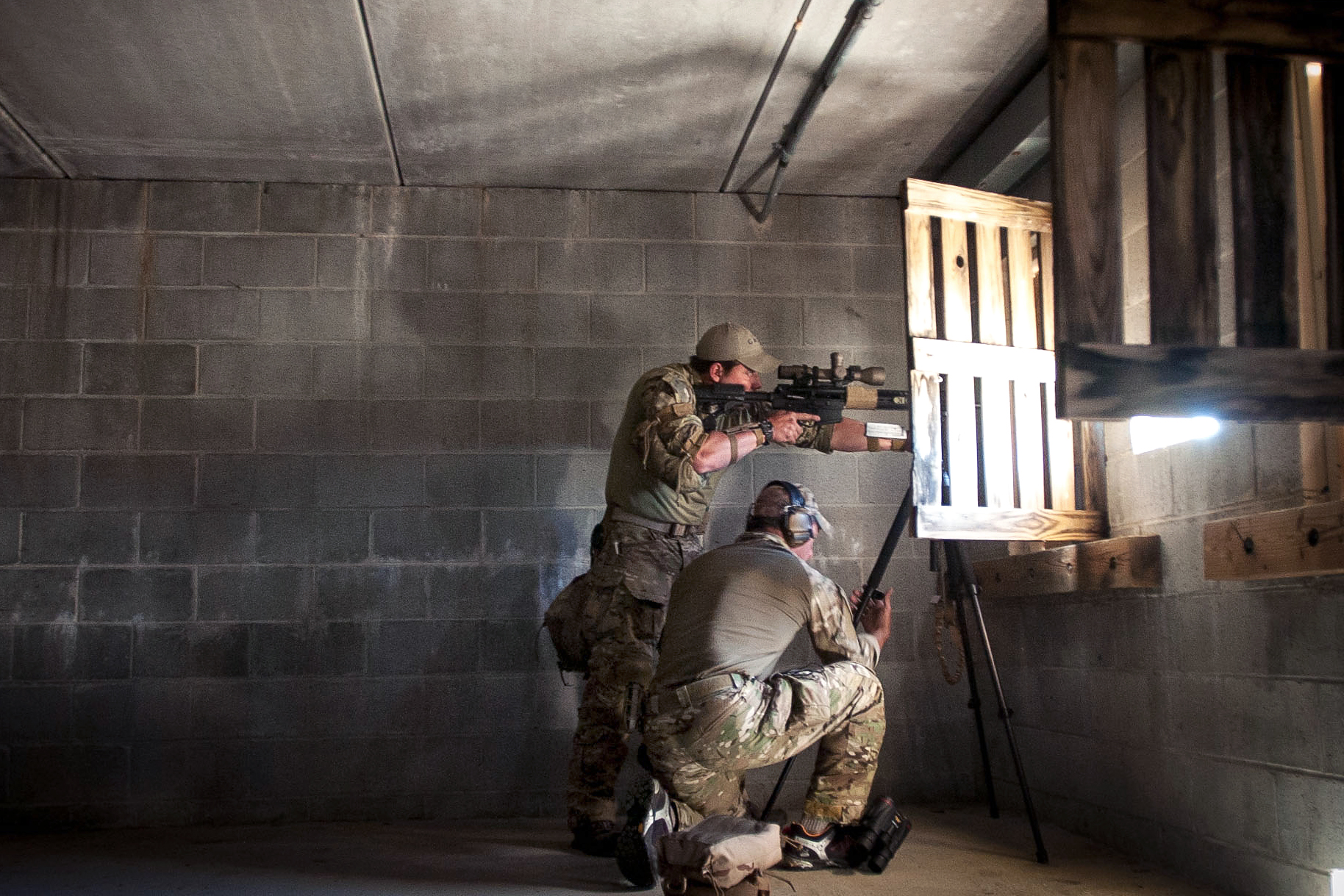 A Special Forces soldier adjusts a tripod while his teammate identifies ...