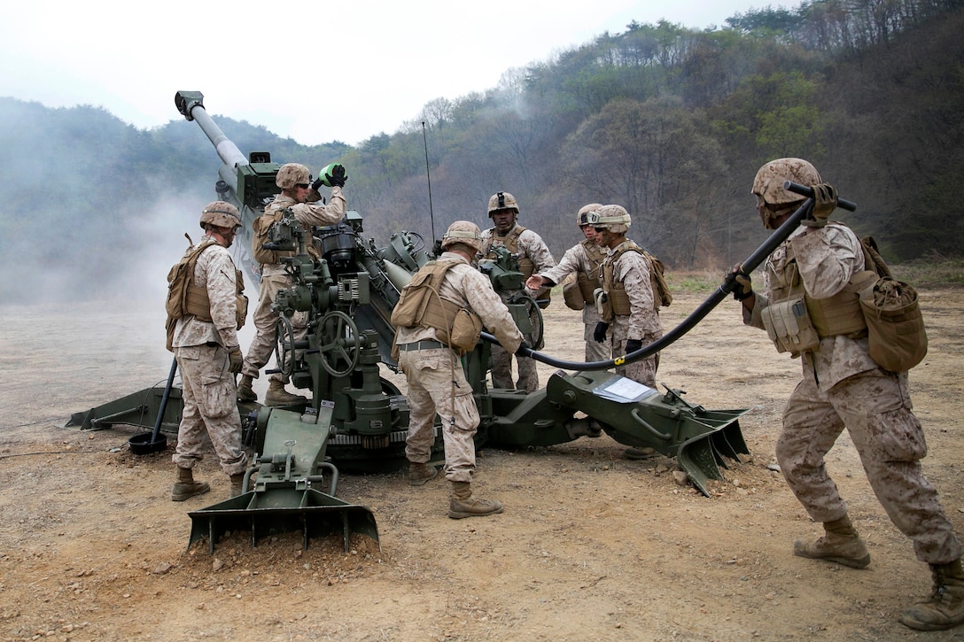 U.S. Marine Corps Lance Cpl. Aaron Manigault, right, pushes a round ...