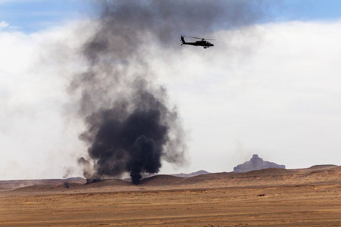 An AH-64 Apache helicopter fires on its target during an exercise near ...