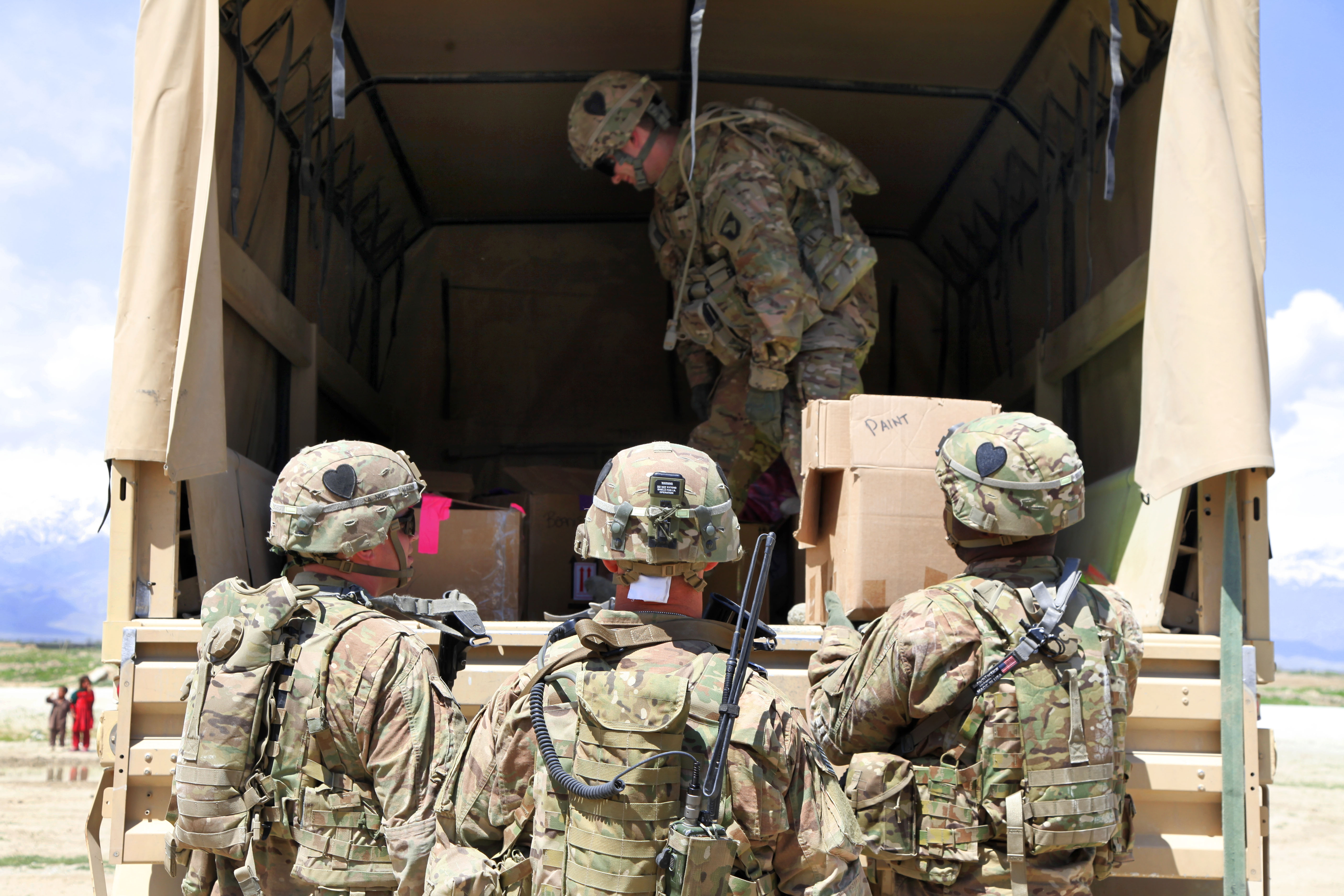 U.S. soldiers unload boxes filled with school supplies from a light ...