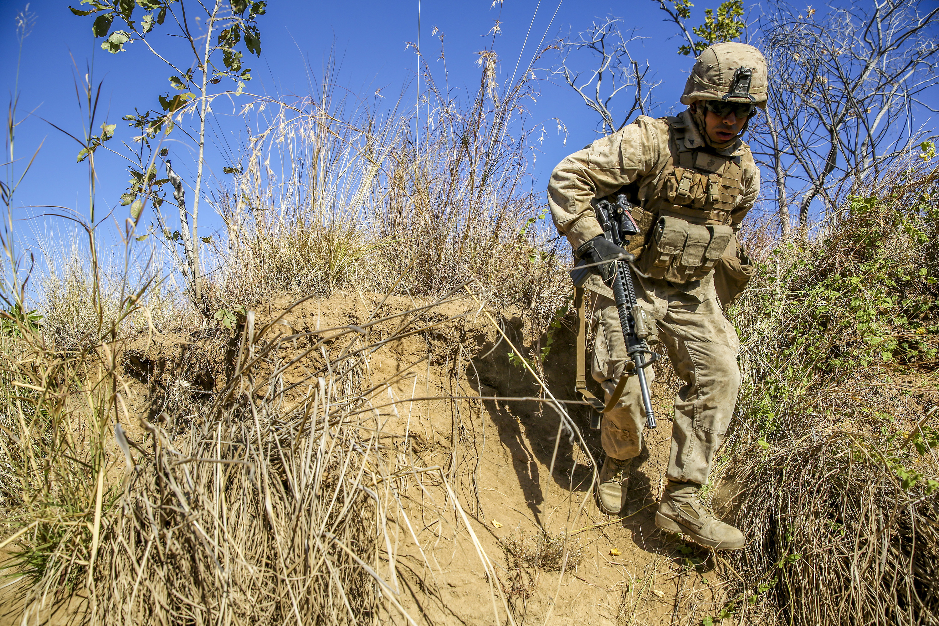 U.S. Marine Corps Lance Cpl. Adan Nevarez jumps into a creek bed during ...