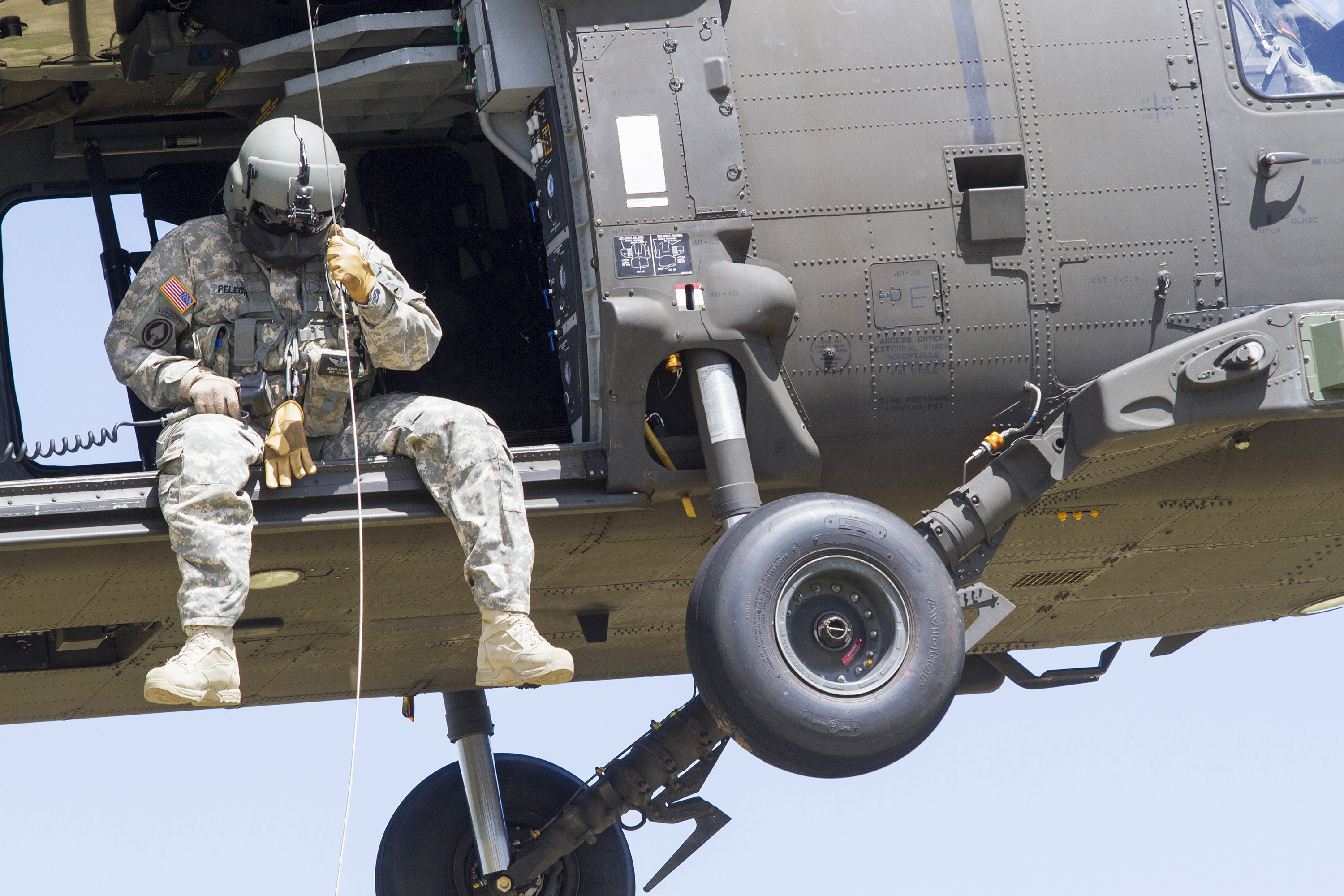 A UH-60M helicopter crew chief uses a hoist to lift a casualty during a ...
