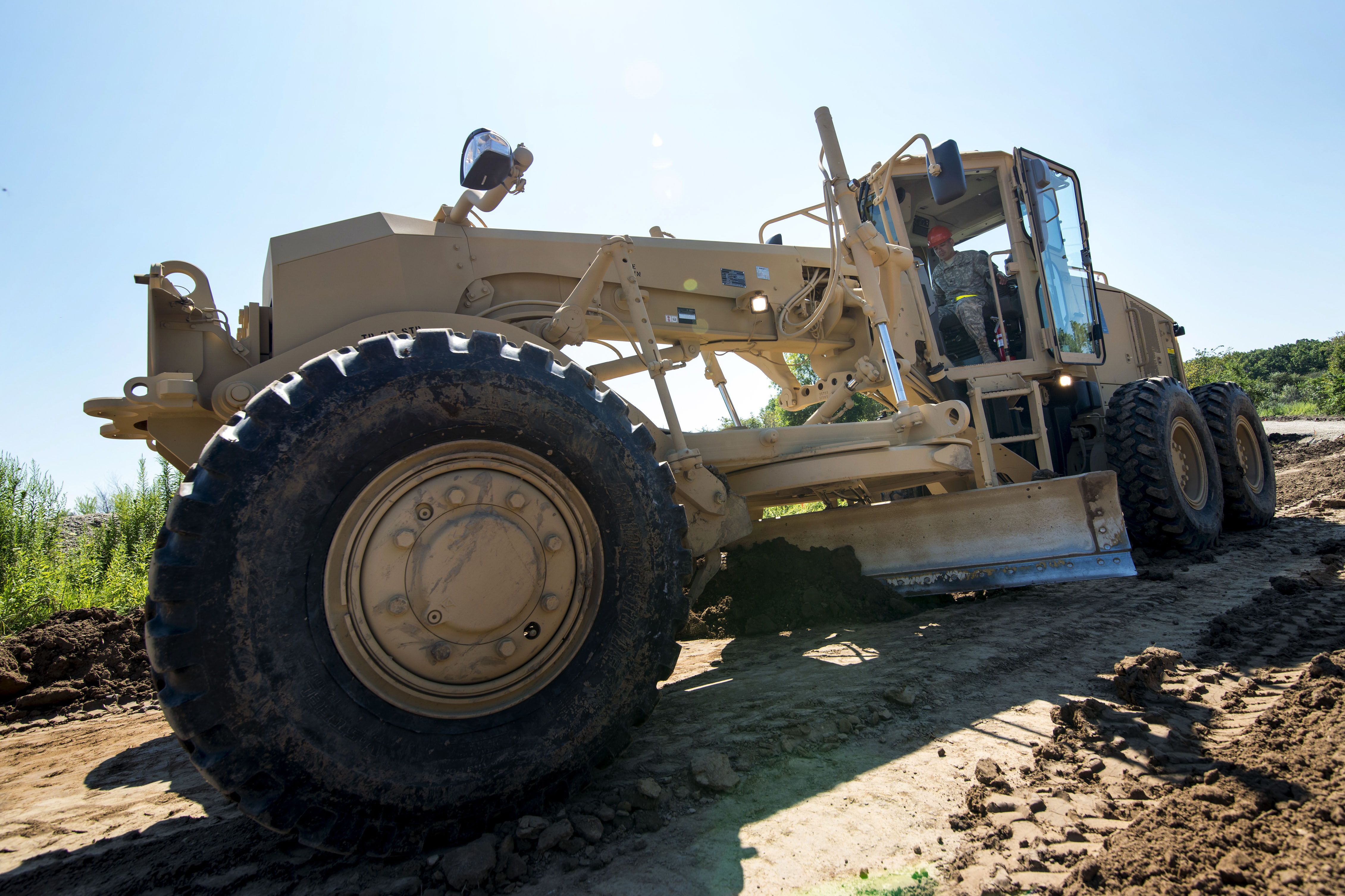Army Sgt. Brian Guzman operates a motor grader to clear a dirt path at ...