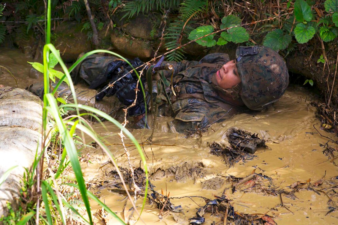 U.S. Marine Corps Lance Cpl. Thomas Kang crawls through mud and under ...