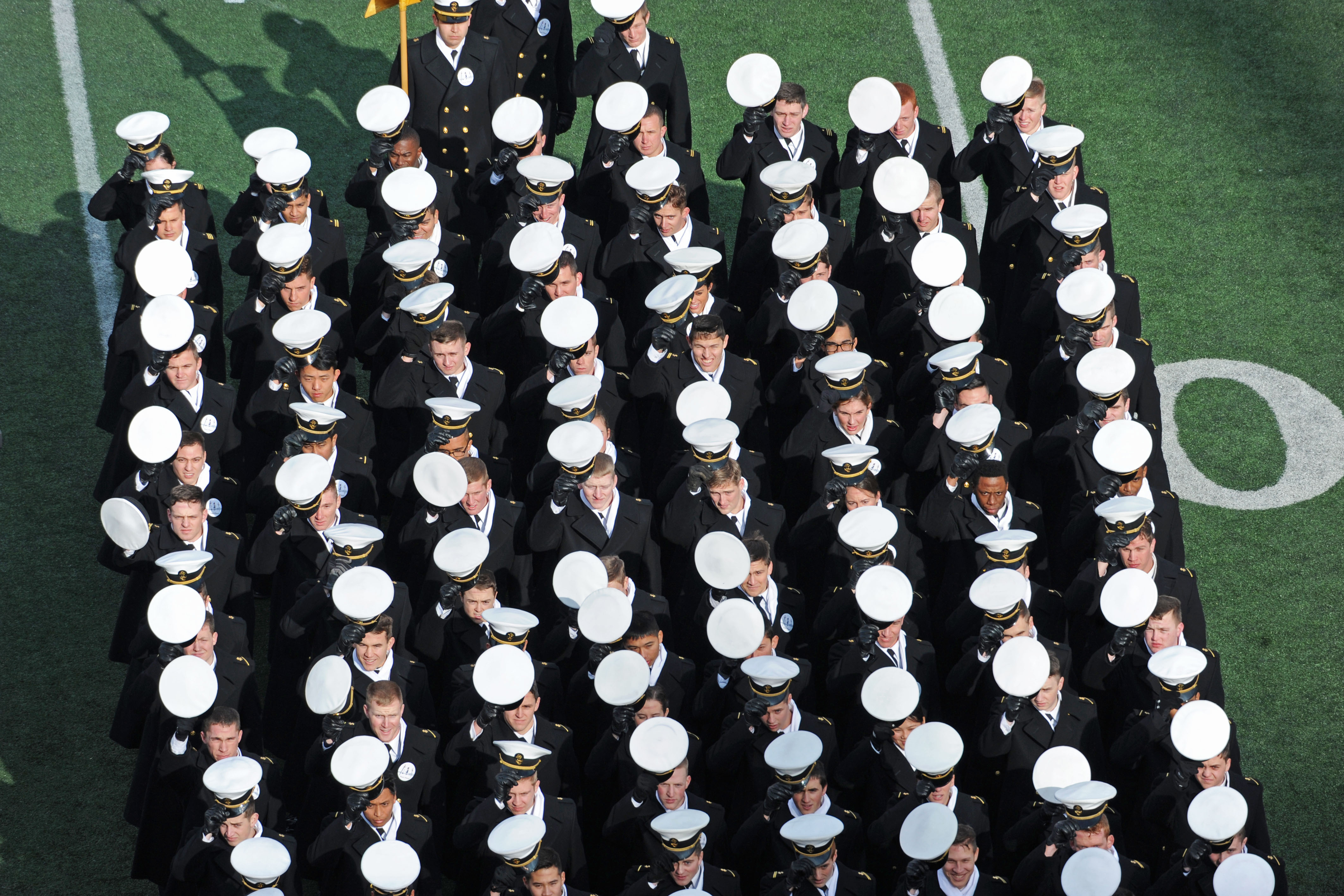 U.S. Naval Academy Midshipmen tip their caps in formation on the field ...