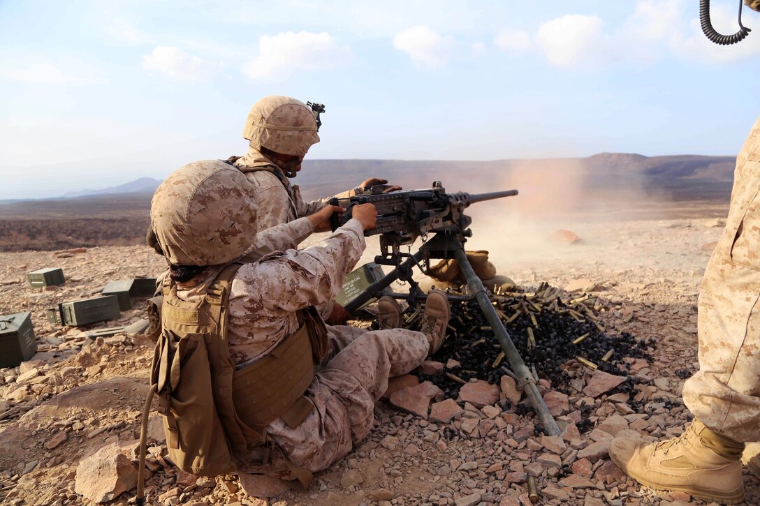 U.S. Marines Corps Cpl. Laura Y. Raga, foreground, fires a .50 cal ...