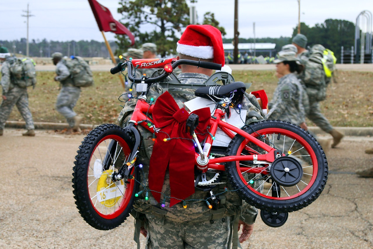 A soldier with a bike tied to his back participates in a toy ruck march ...