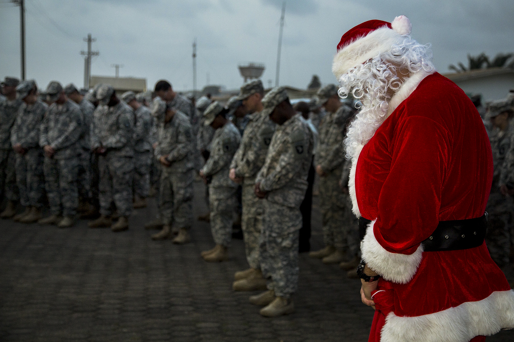 Santa Claus and service members bow their heads in prayer during the ...