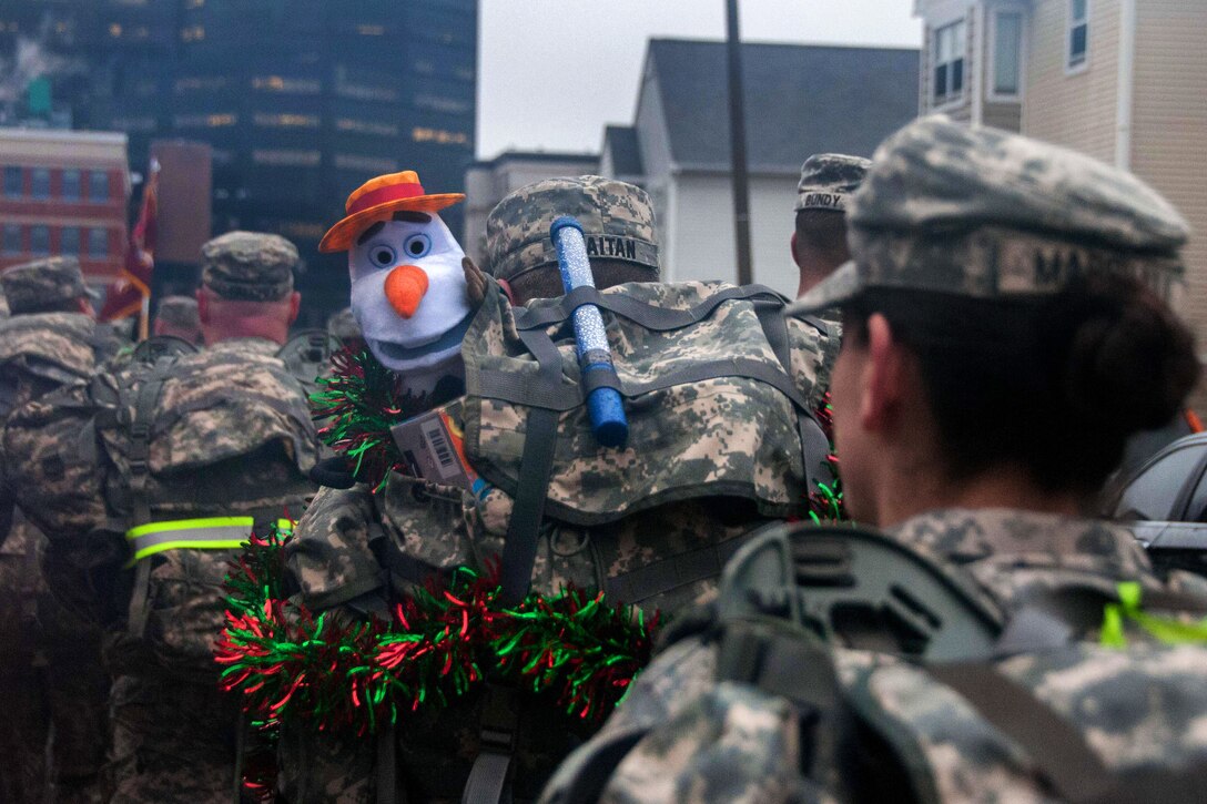 Army Sgt. 1st Class Jamie Gaitan, center, with a plush snowman tuck ...