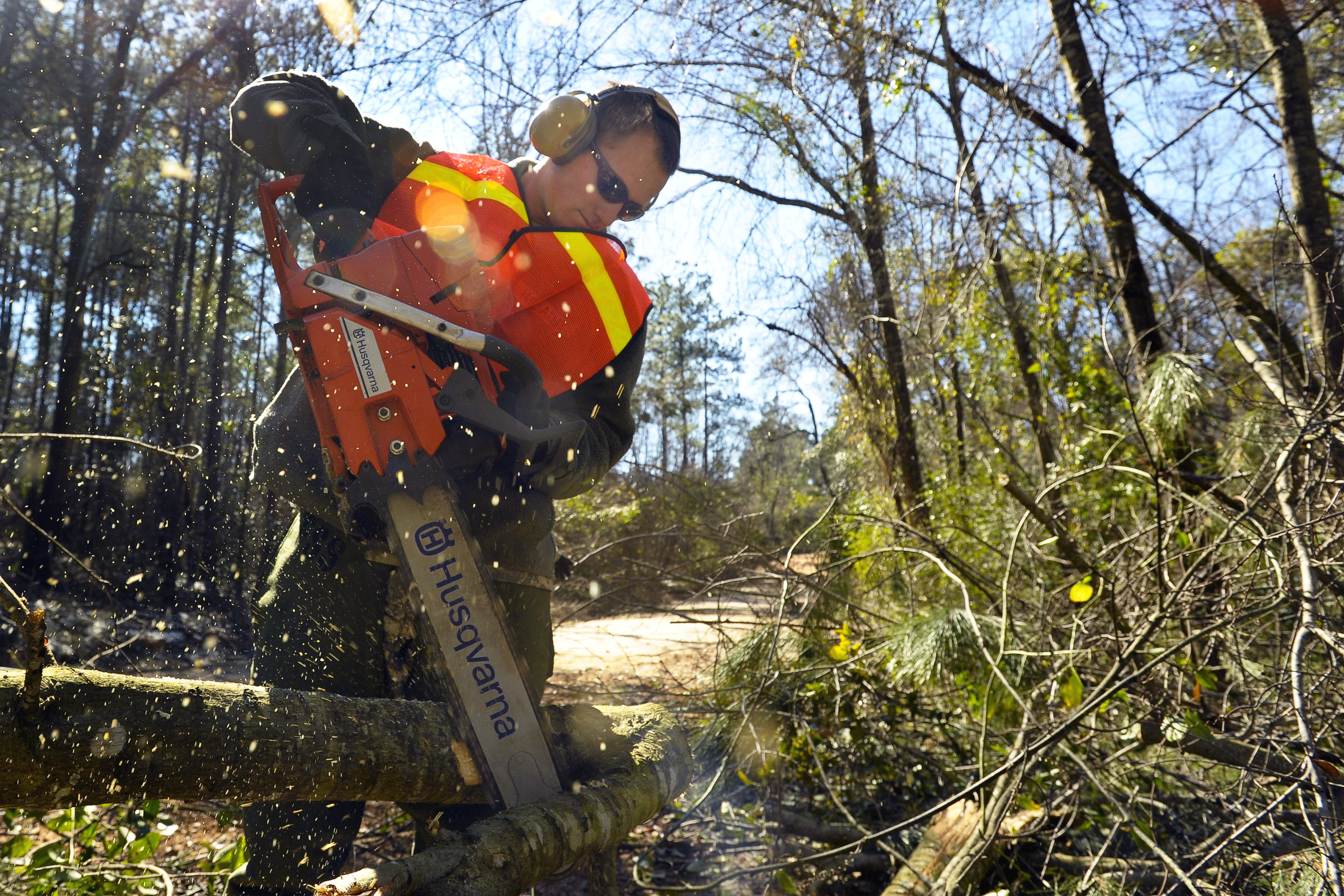 Army Spc. Cody Fields uses a chain saw to cut through a downed tree on ...